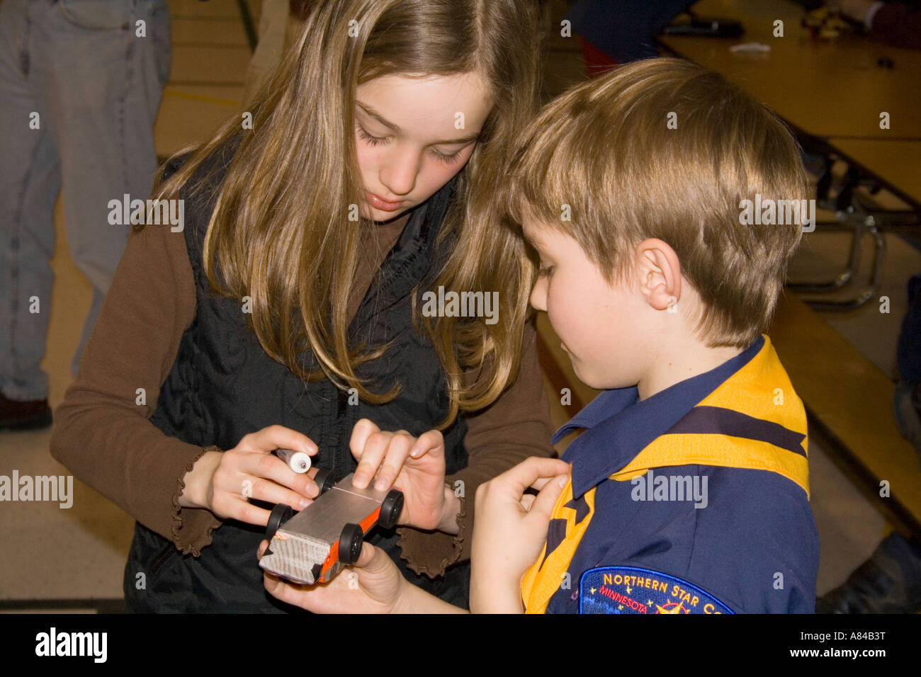Sister helping Cub Scout lubricate race car Pinewood Derby age 14 and 7 ...
