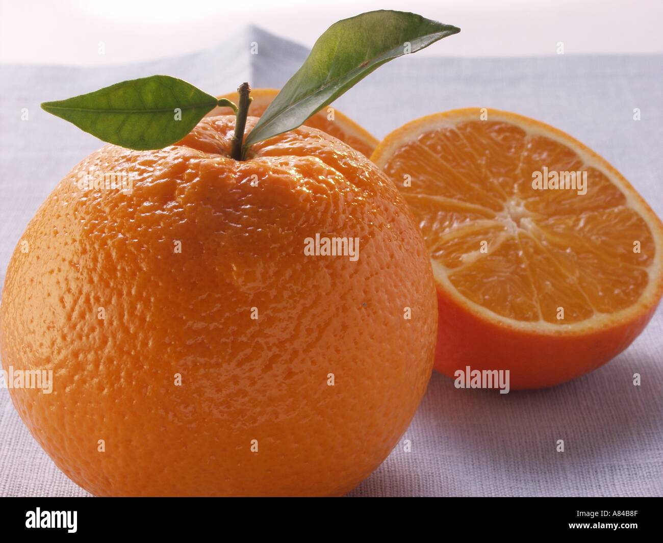 Orange with stalk and leaves and half an orange Stock Photo - Alamy