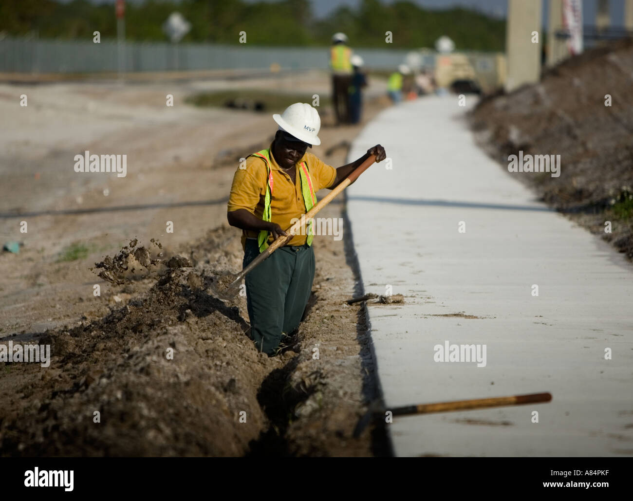 Worker digging a trench on the side of a road Stock Photo - Alamy
