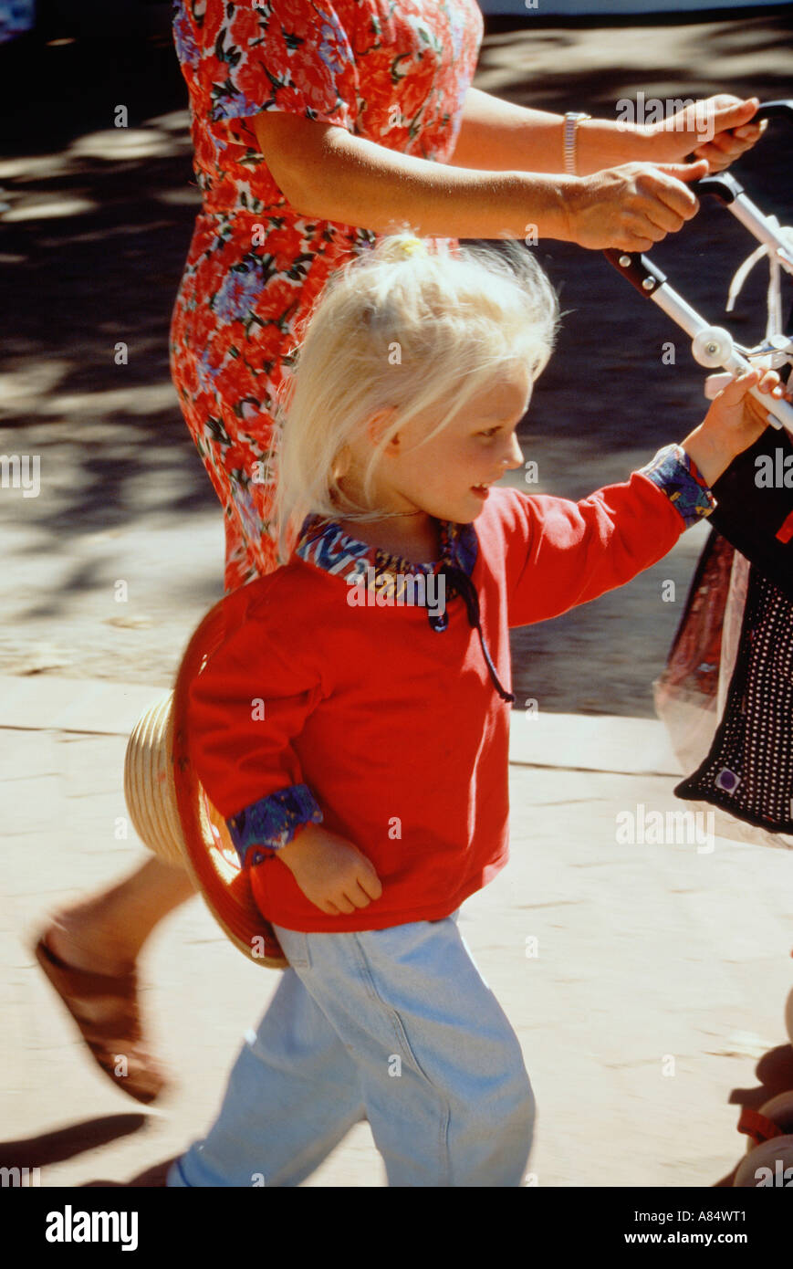 Mother and child pushing pram along city pavement Stock Photo - Alamy