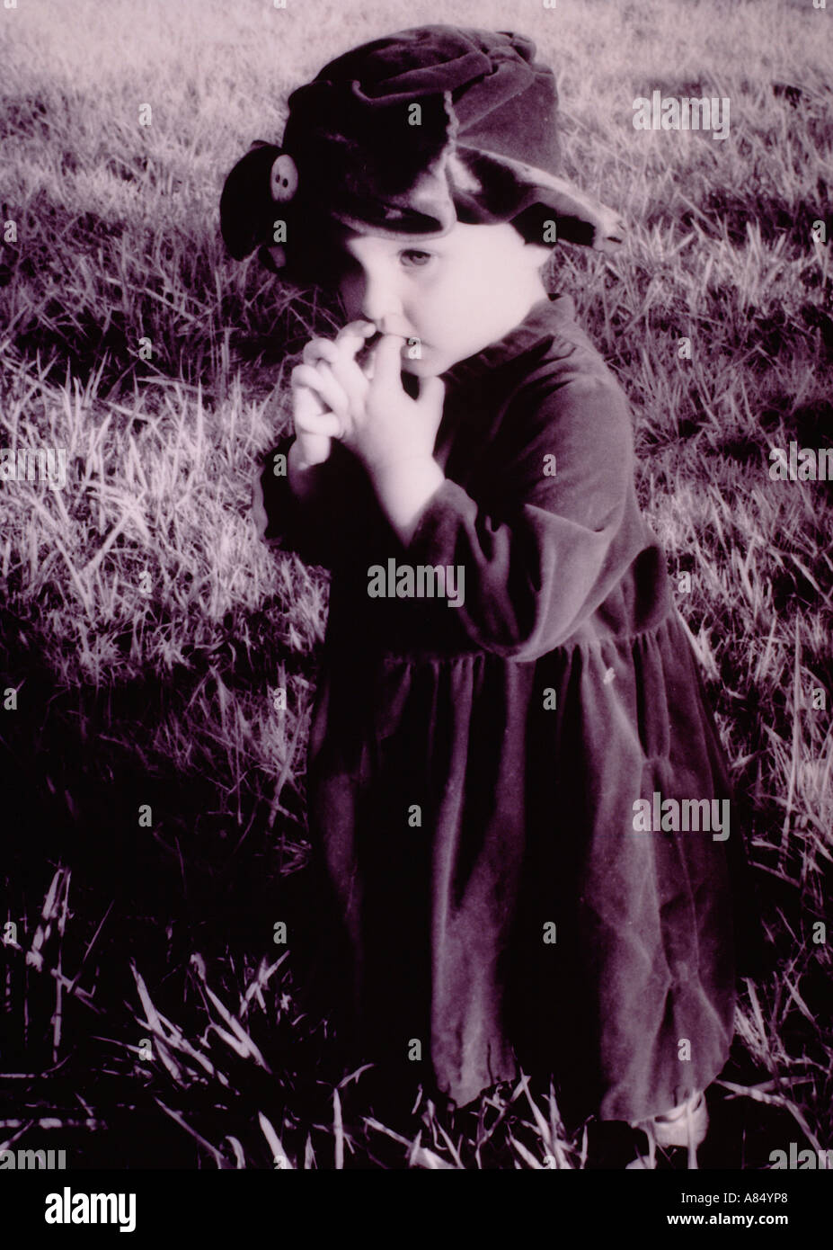 Little girl child with anxious expression standing outdoors in field ...