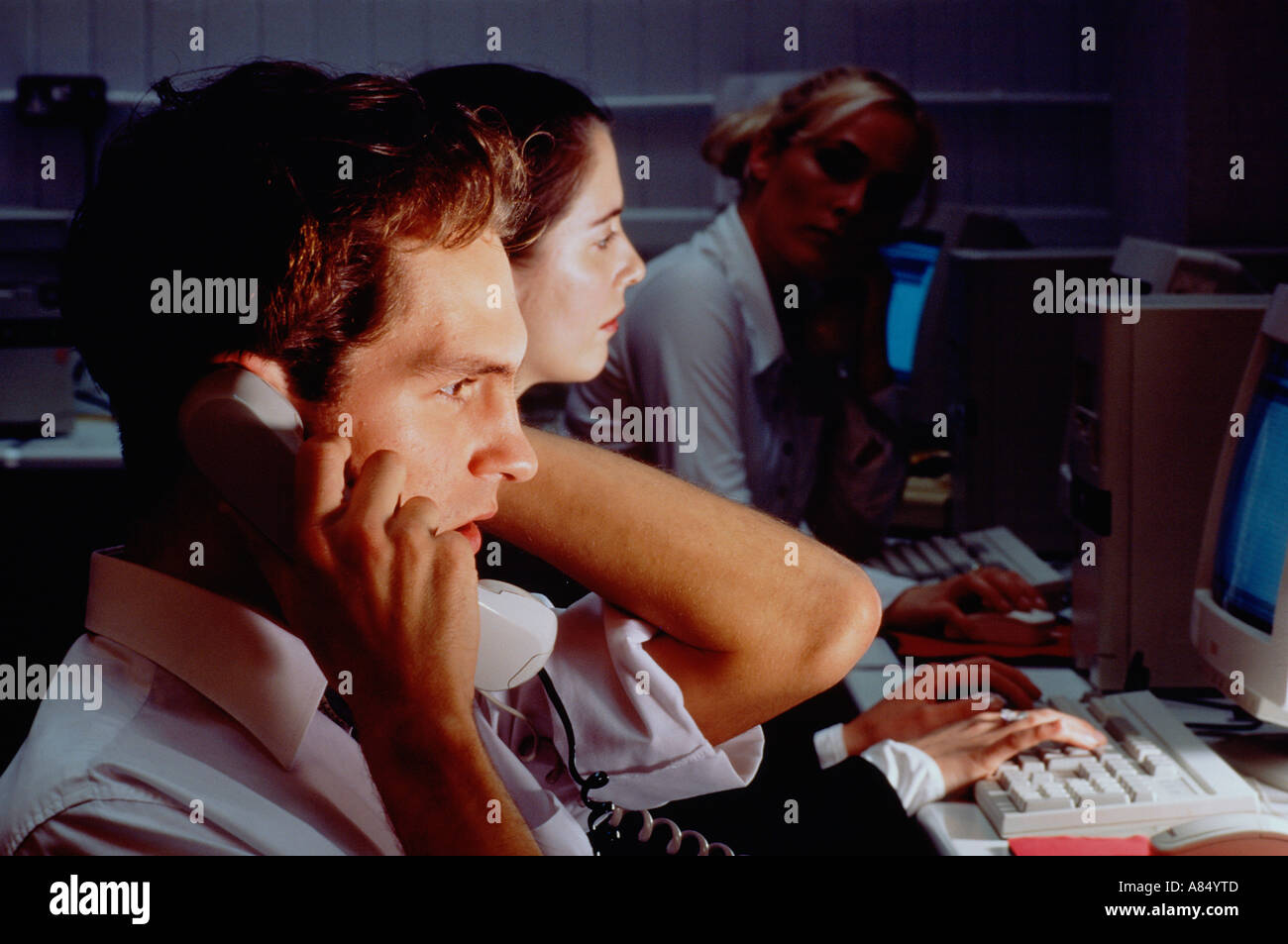 Call centre telephone operators with computer monitor screens at night ...