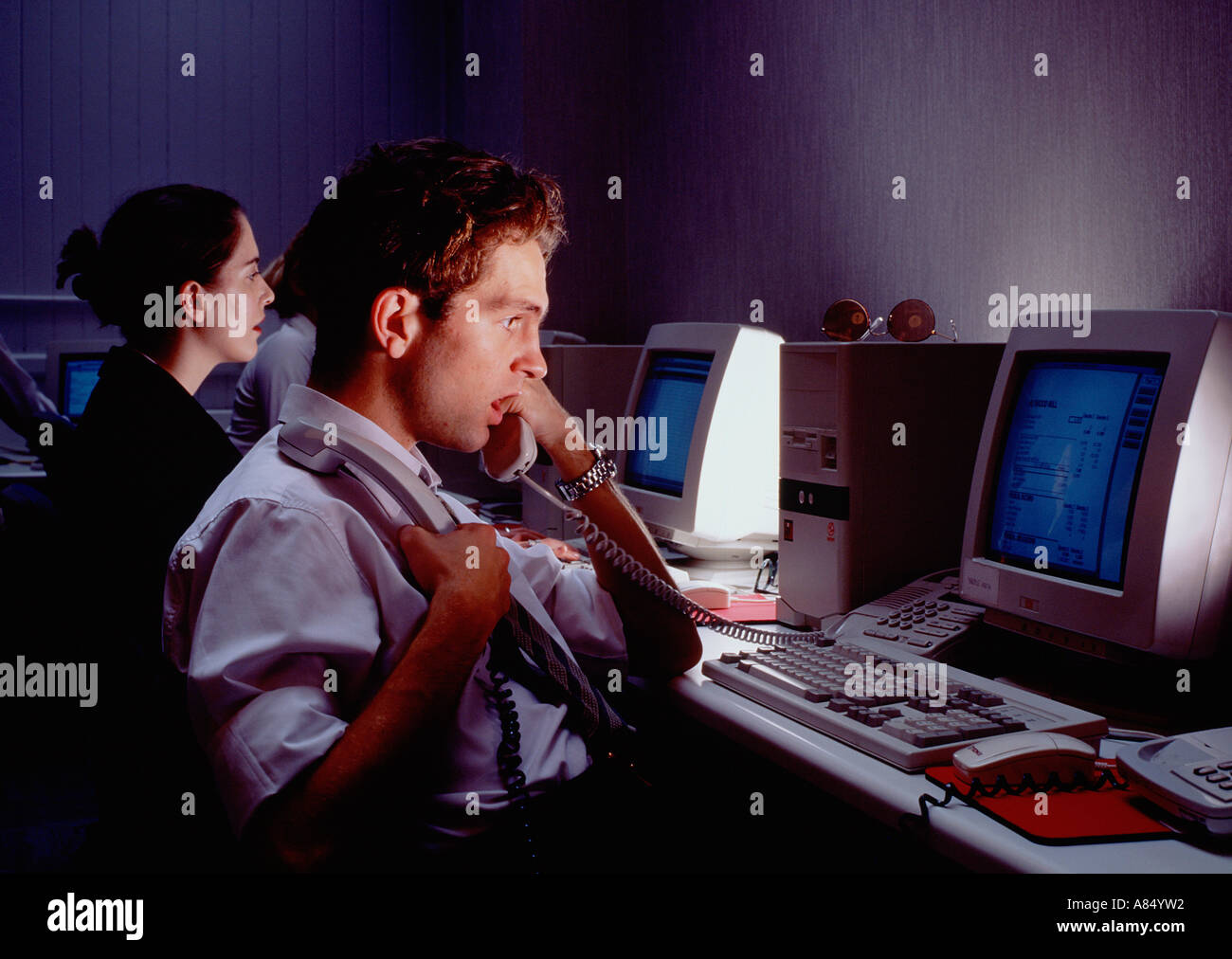 Call center telephone operators. Man using telephone whilst referring ...