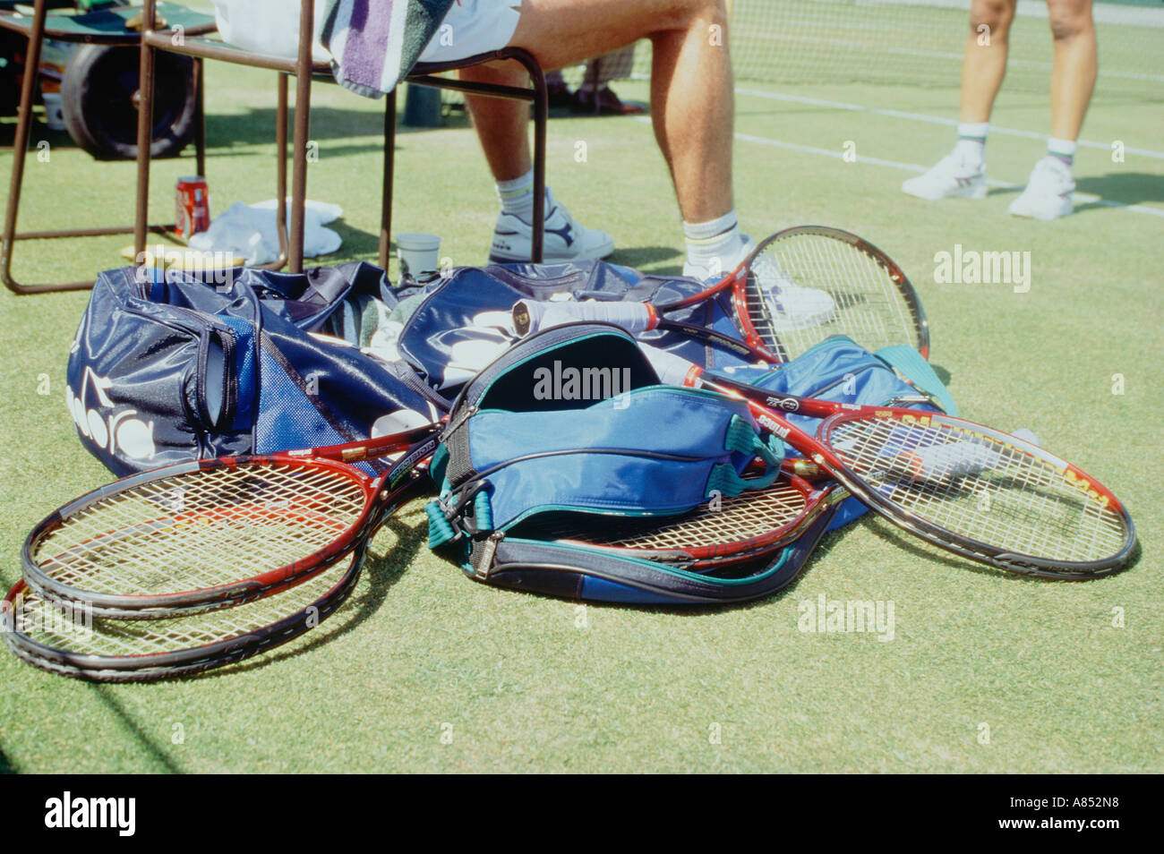 Edge of tennis court scene with close-up of rackets and players' legs ...