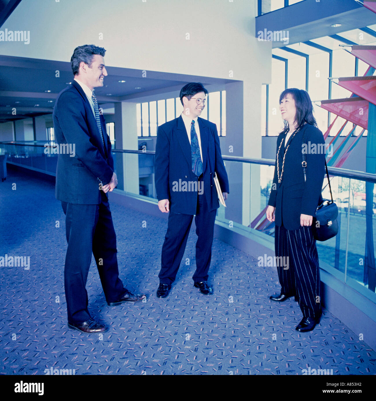 Two men and a woman in business suits standing on mezzanine inside ...