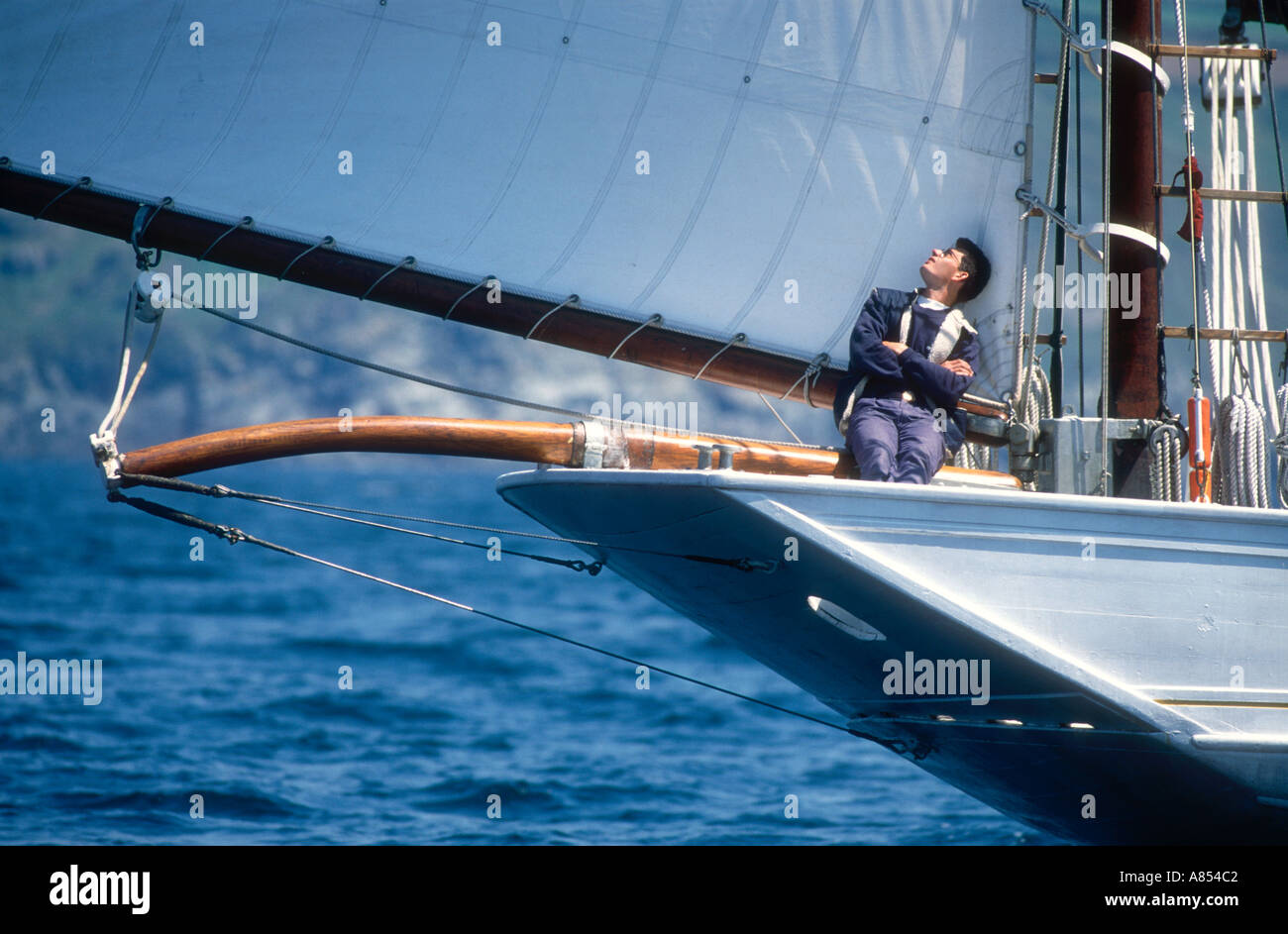 A crew member at the stern of the French navy owned gaff yawl Mutin a ...
