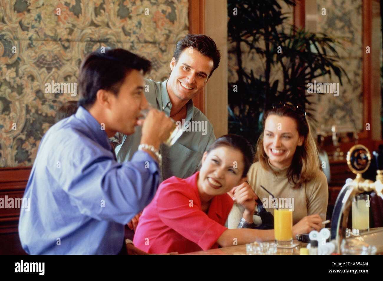 Four young people at hotel bar drinking contest Stock Photo - Alamy