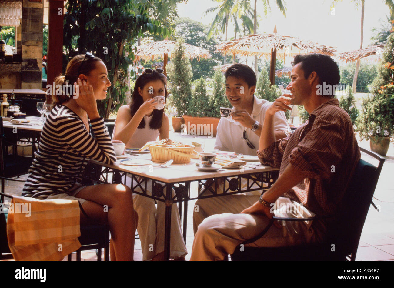 Four friends sitting on outdoor terrace of café restaurant. Singapore ...
