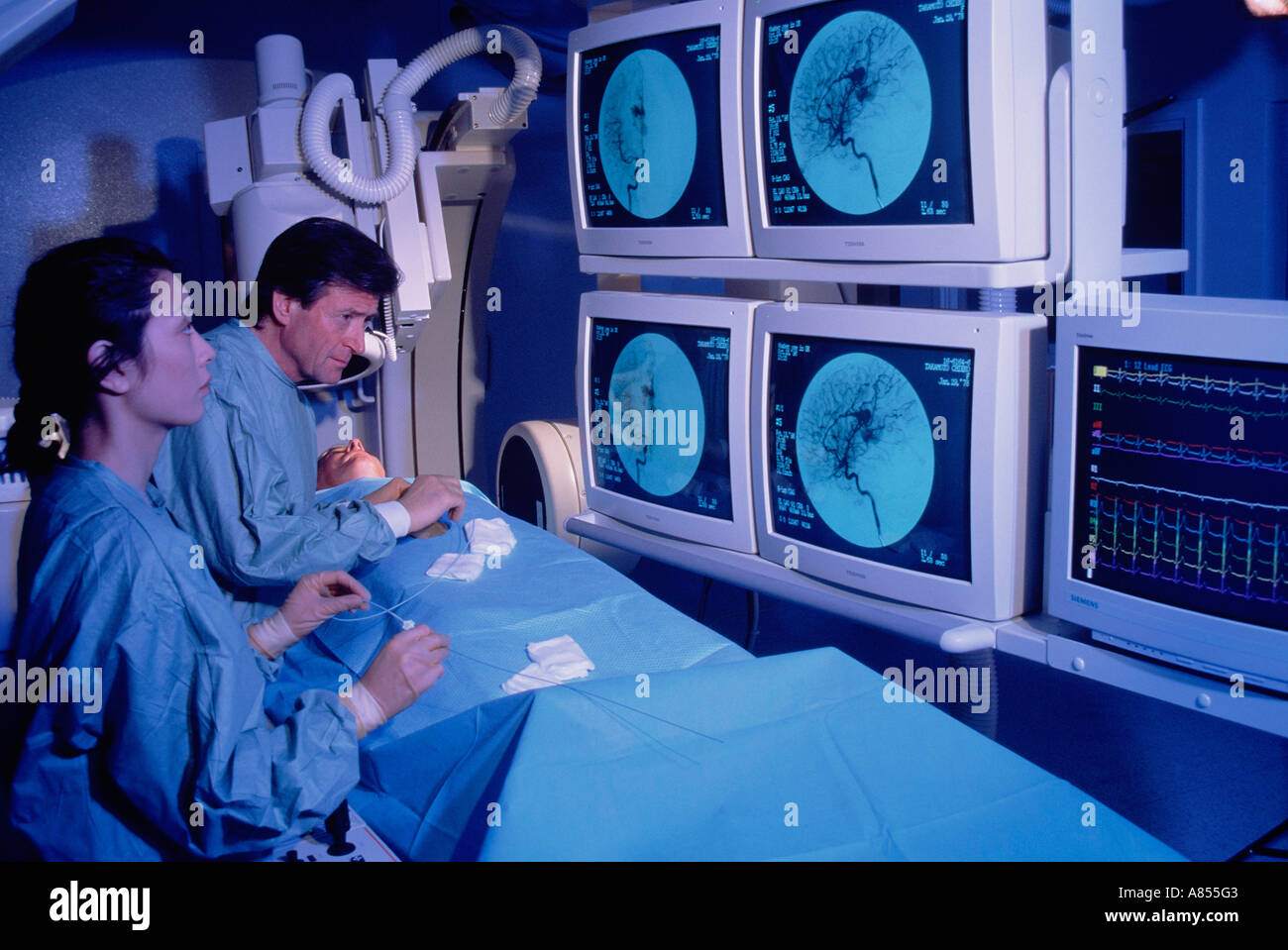Surgeon and nurse with patient in hospital Angiography scanning room ...