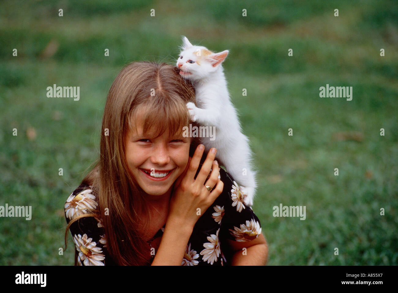Young girl outdoors with pet kitten climbing on her head Stock Photo ...