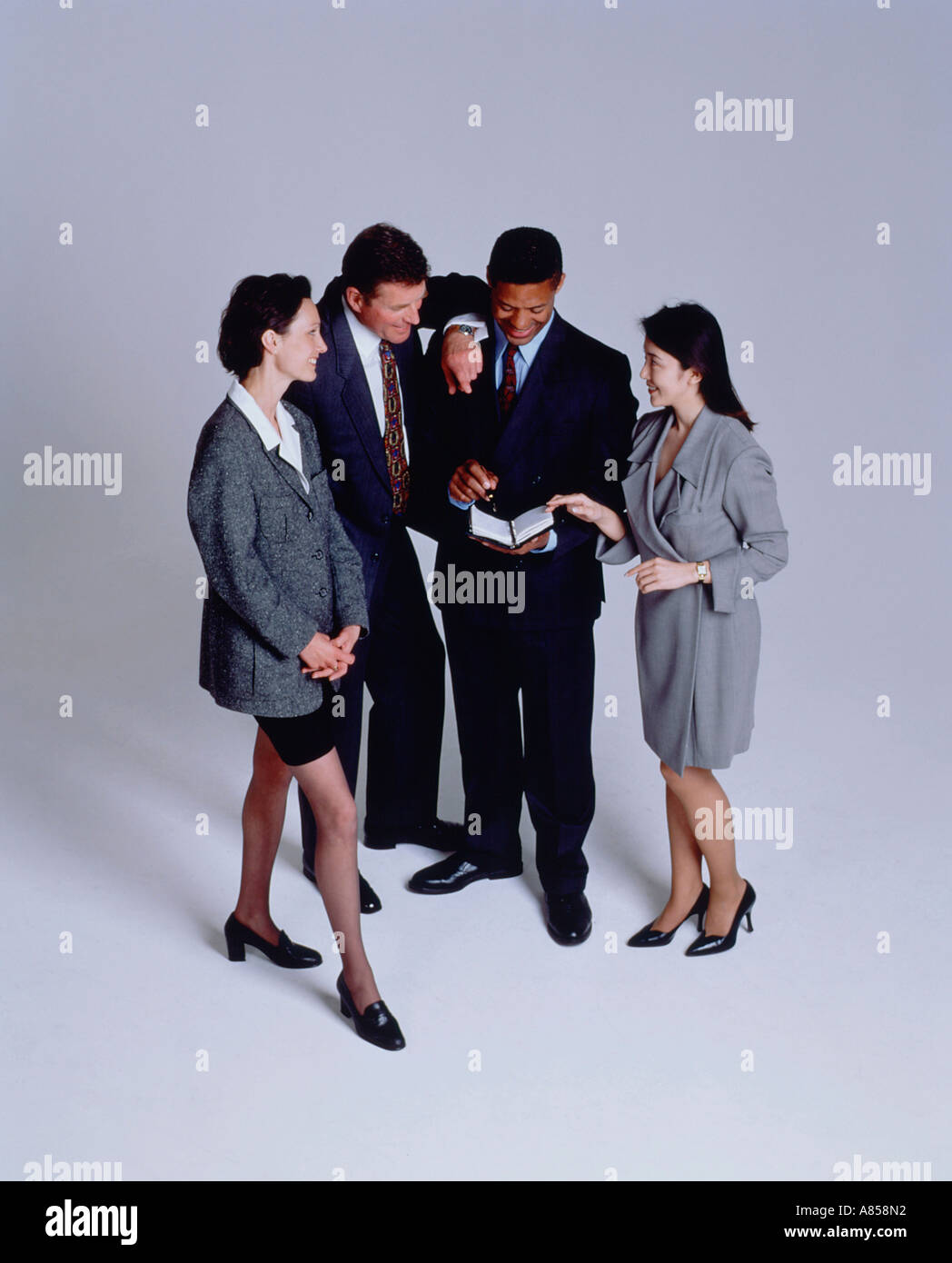 Indoor studio full length image of four people standing talking to each ...