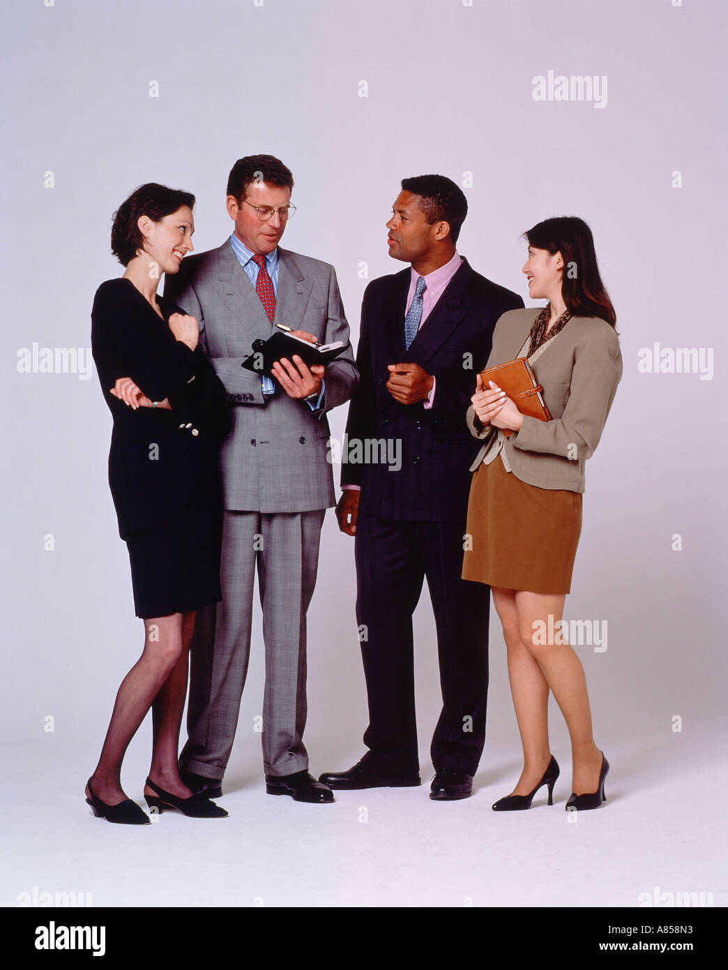 Indoor studio full length image of four people standing talking to each ...