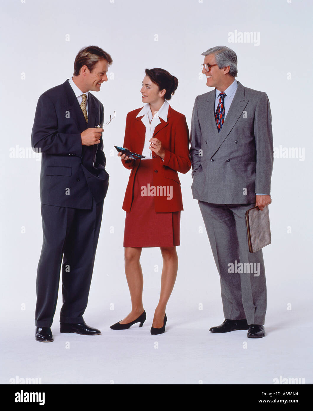 Indoor studio full length image of three people standing talking to ...