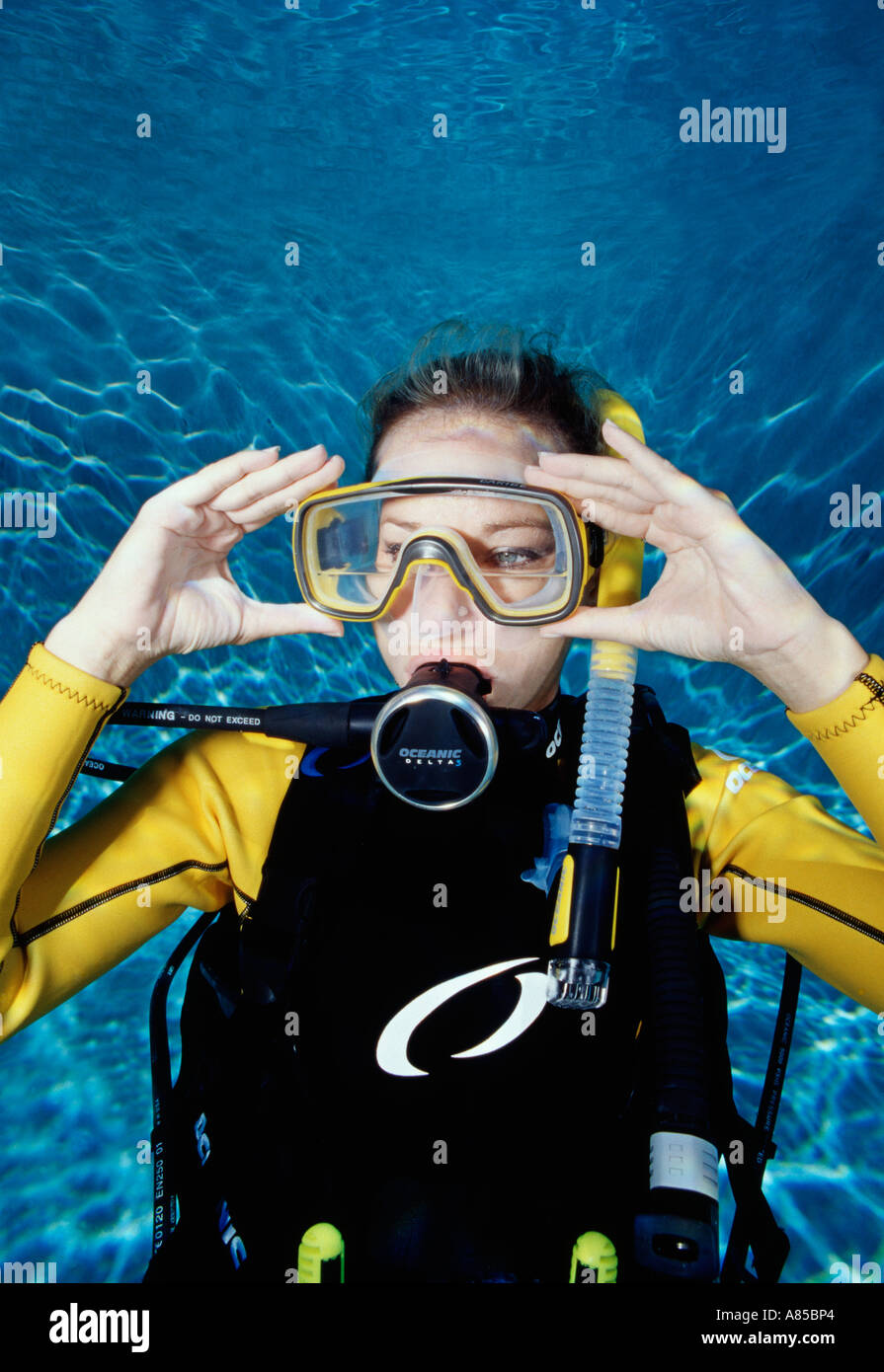 Woman diver holding mask with two hands to clear Stock Photo - Alamy