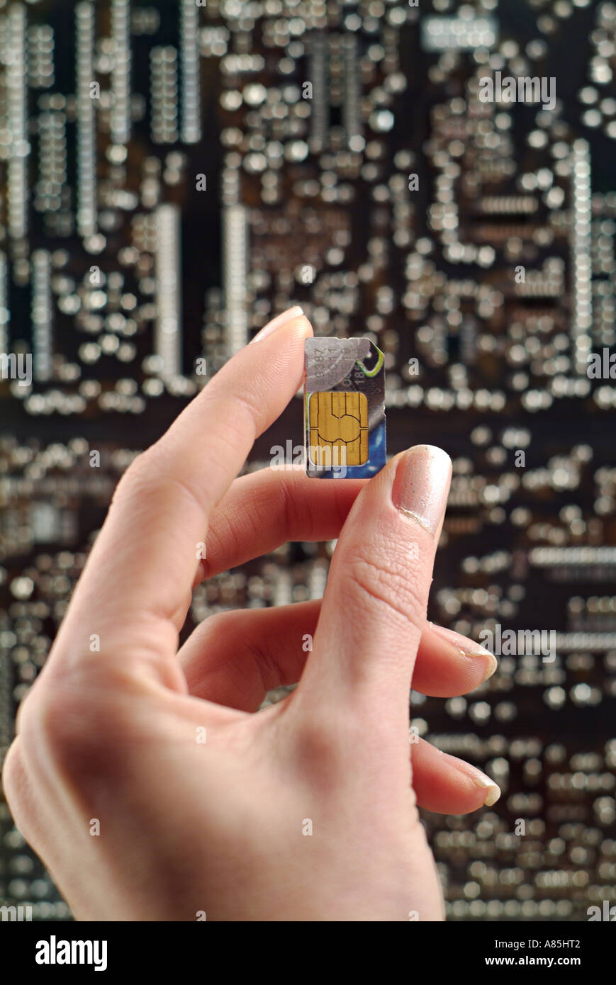 Mobile phone SIM card held between the fingers of a female with an ...