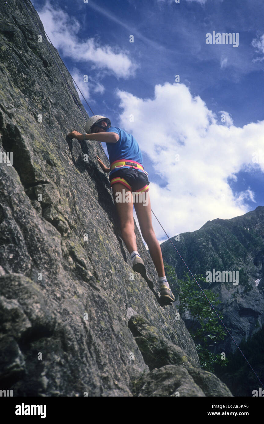 Young man rock climbing up a vertical cliff Stock Photo - Alamy