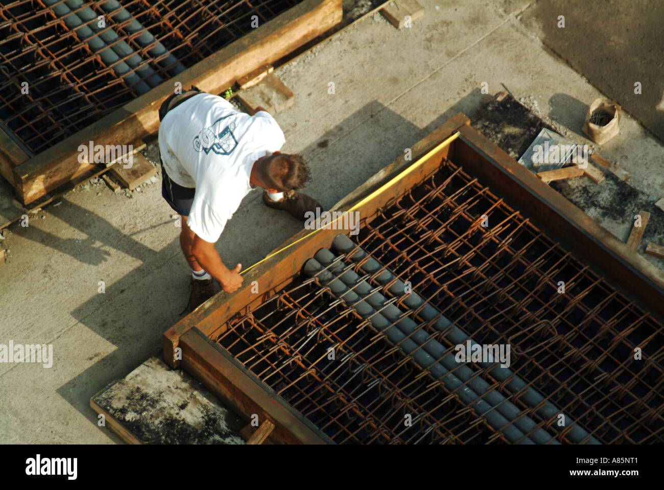 Palma workman measuring timber formwork around steel reinforcement ...