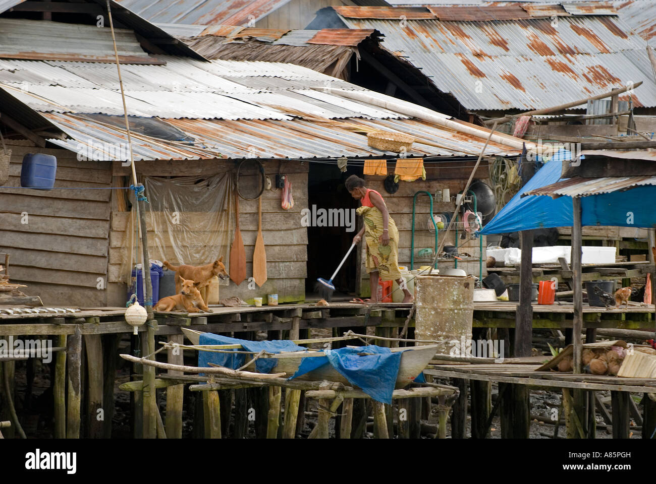 Indonesian woman cleaning her veranda in a village along Waigeo Island ...