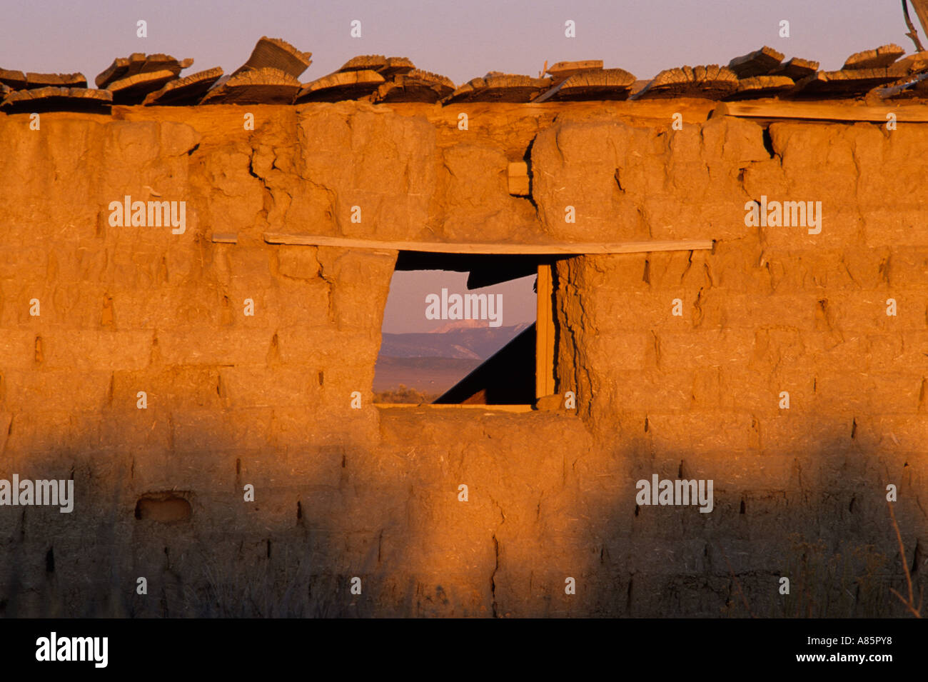 A distant mountain framed in the window of an abandoned mud brick cabin ...