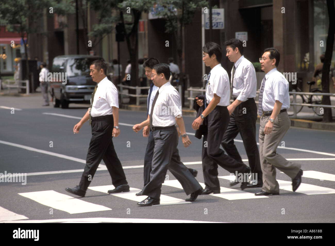 A group of Tokyo "sarariman" (businessmen) crossing the street in the ...