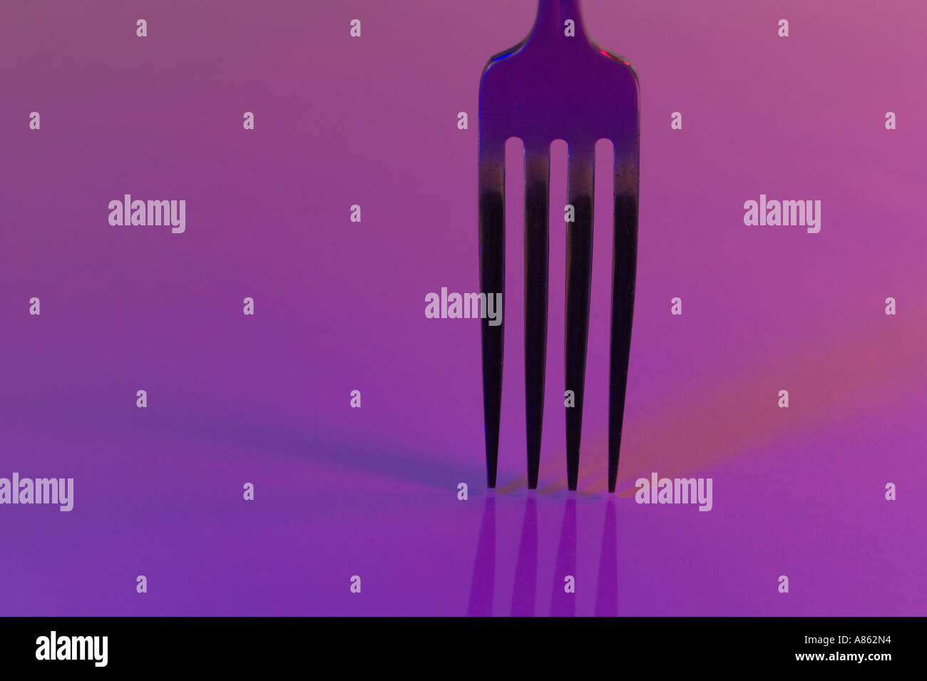 A fork and its reflection with red, blue and violet light Stock Photo ...