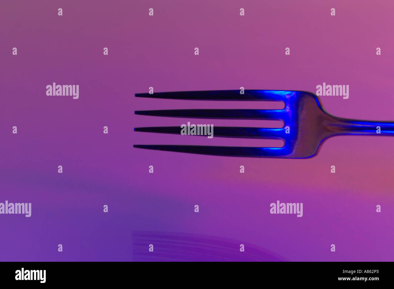 A fork and its reflection with red, blue and violet light Stock Photo ...