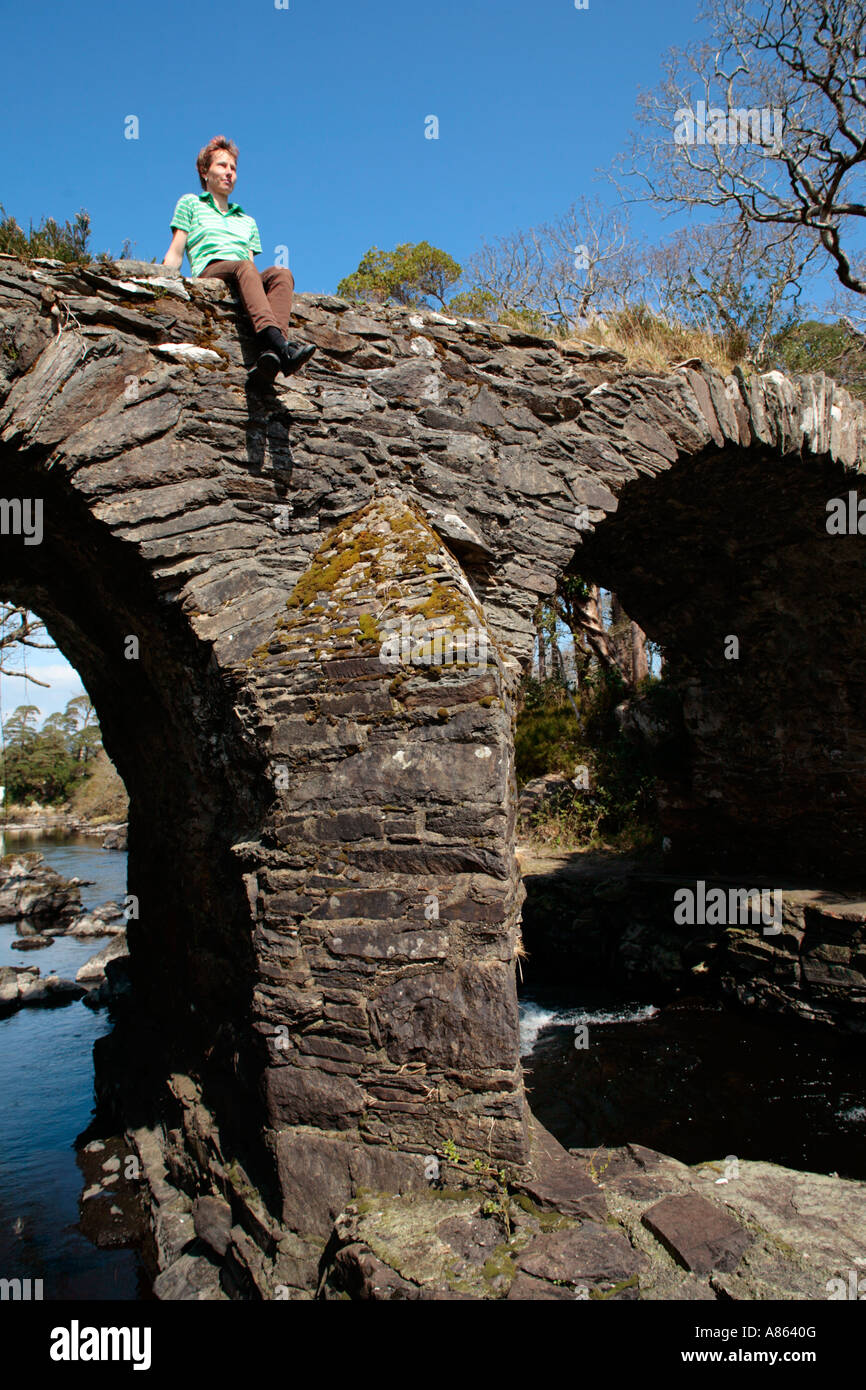 young woman sitting on Old Weir Bridge at Killarney Nationalpark in ...