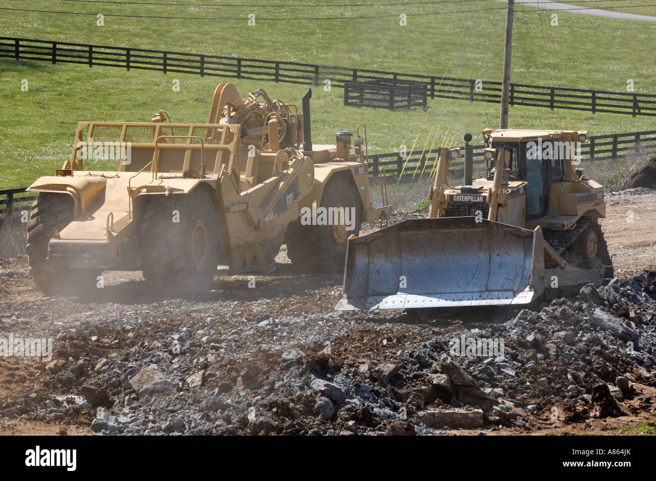 Wheel tractor scrapper and bulldozer working at highway construction ...