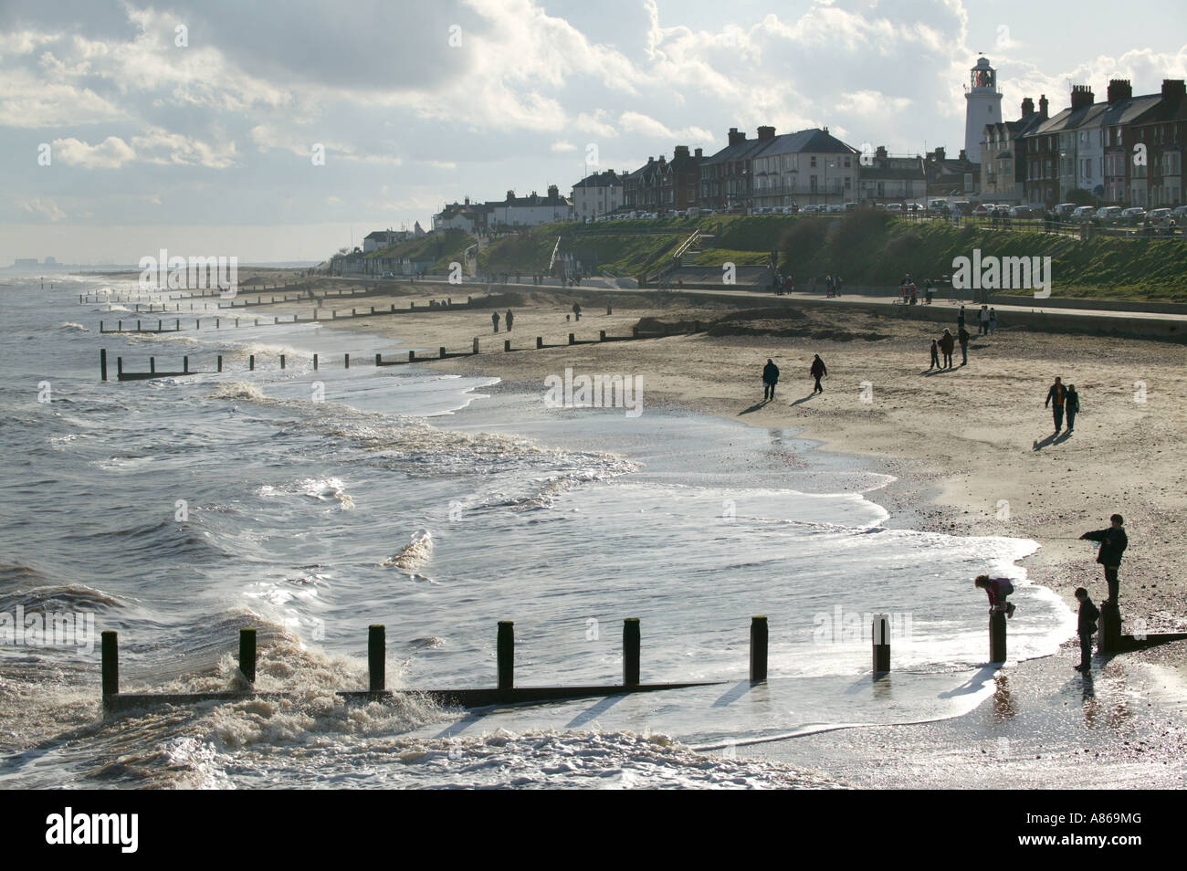 Spring beach landscape with small family playing on the edge of the sea ...