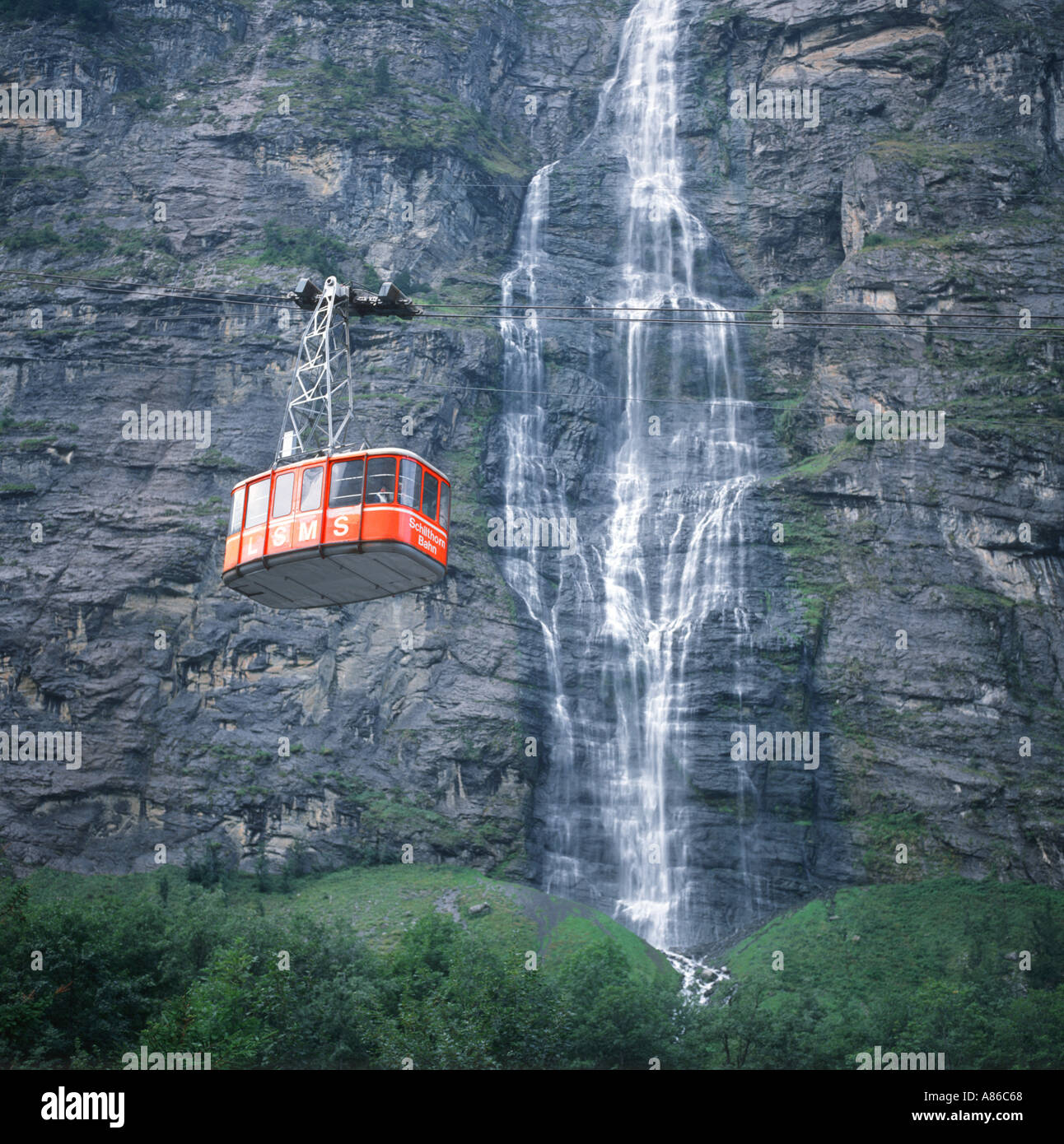 cable car travels past a waterfall in the Alps near Lauterbrunnen ...