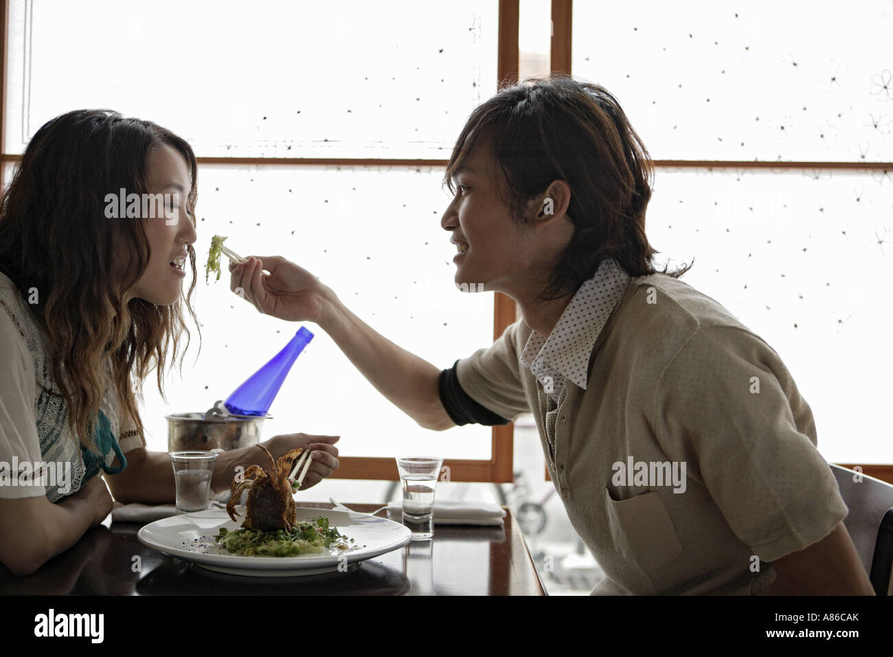 Young couple eating, side view Stock Photo - Alamy
