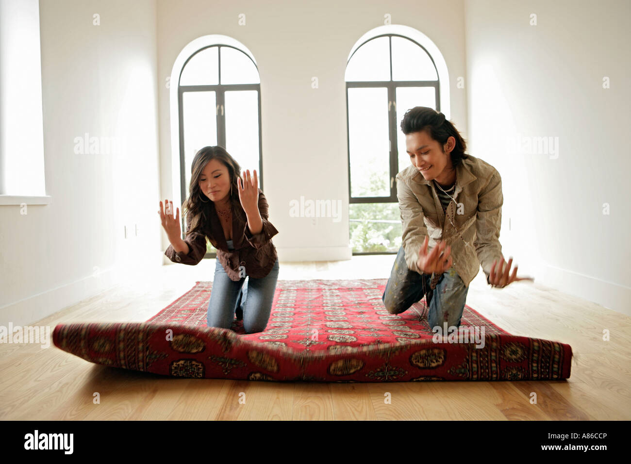 Two people kneeling on carpet, front view Stock Photo - Alamy
