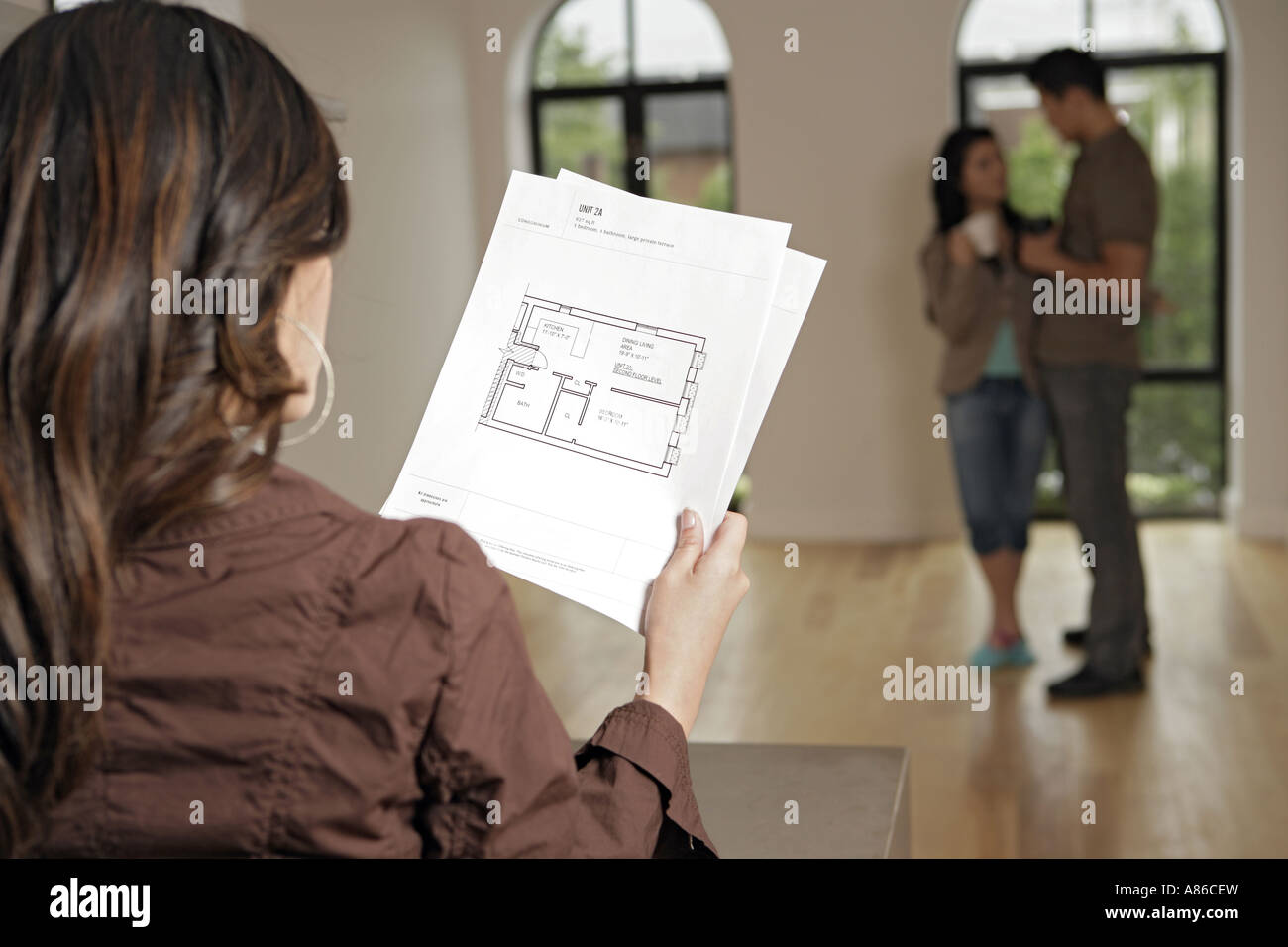 Young women holding paper while couple in background, rear view Stock ...