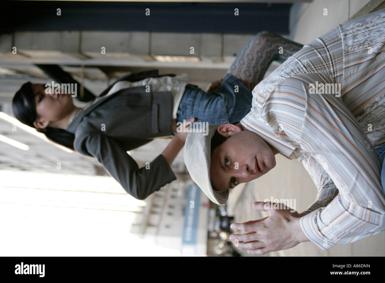 Woman standing, man sitting looking at camera Stock Photo - Alamy