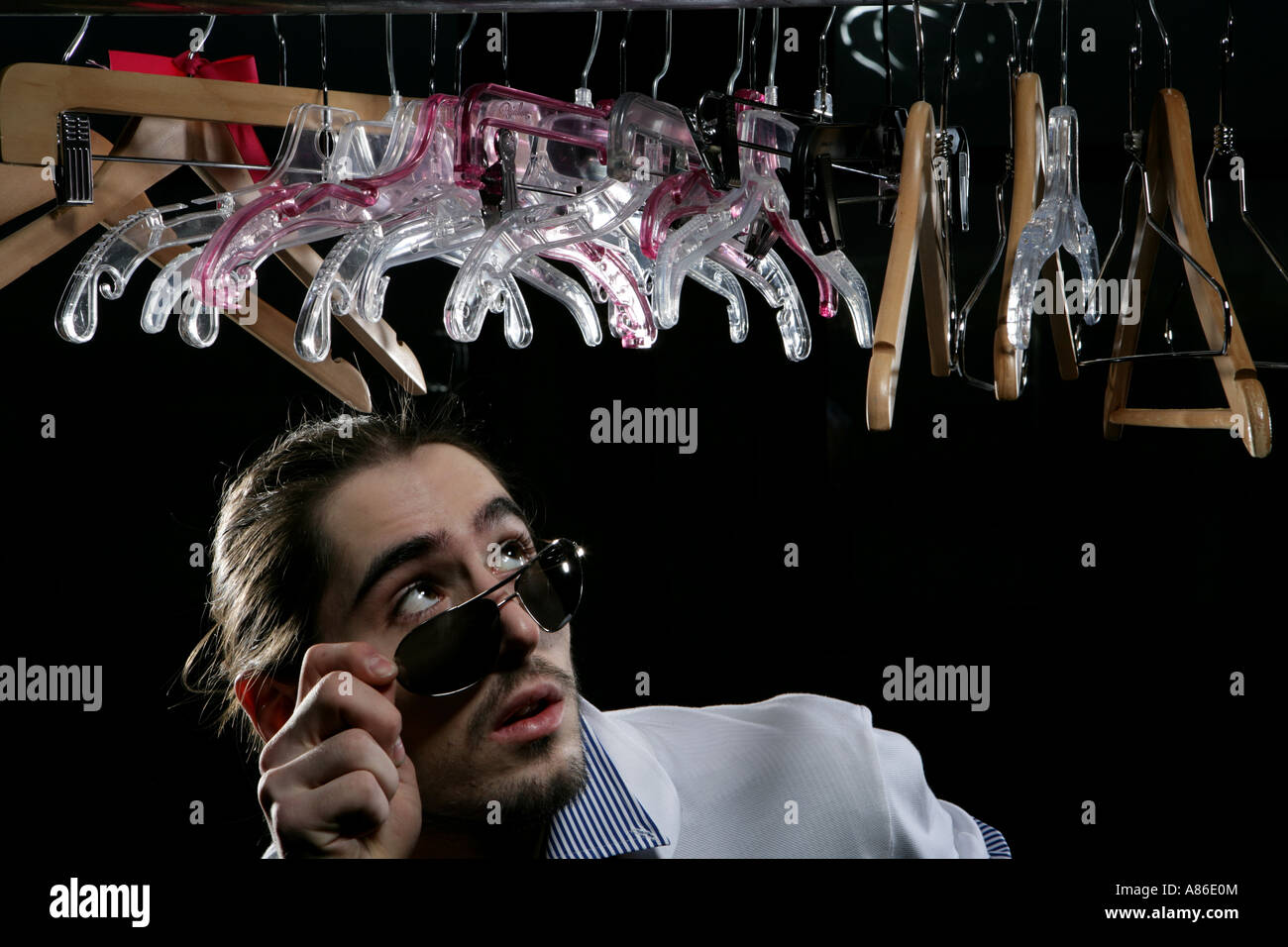 Young man standing beneath a row of hangers Stock Photo - Alamy