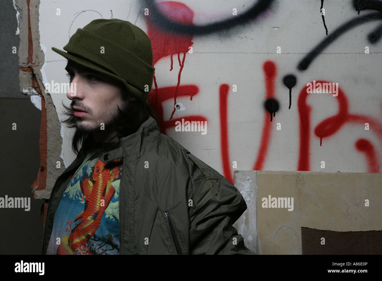 Side view of a young man standing in front of a tagged wall Stock Photo ...