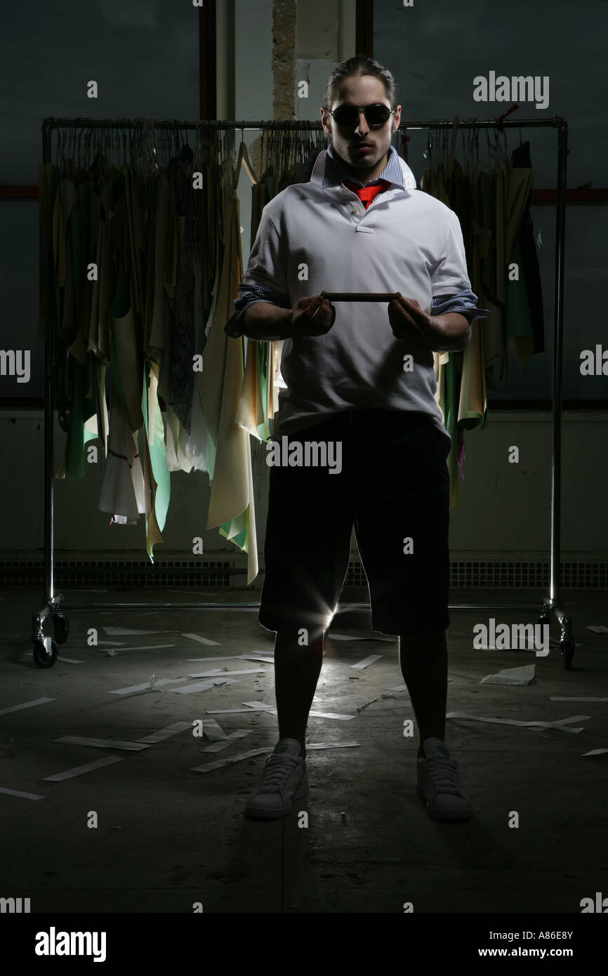 Young man standing in front of a clothing rack Stock Photo - Alamy