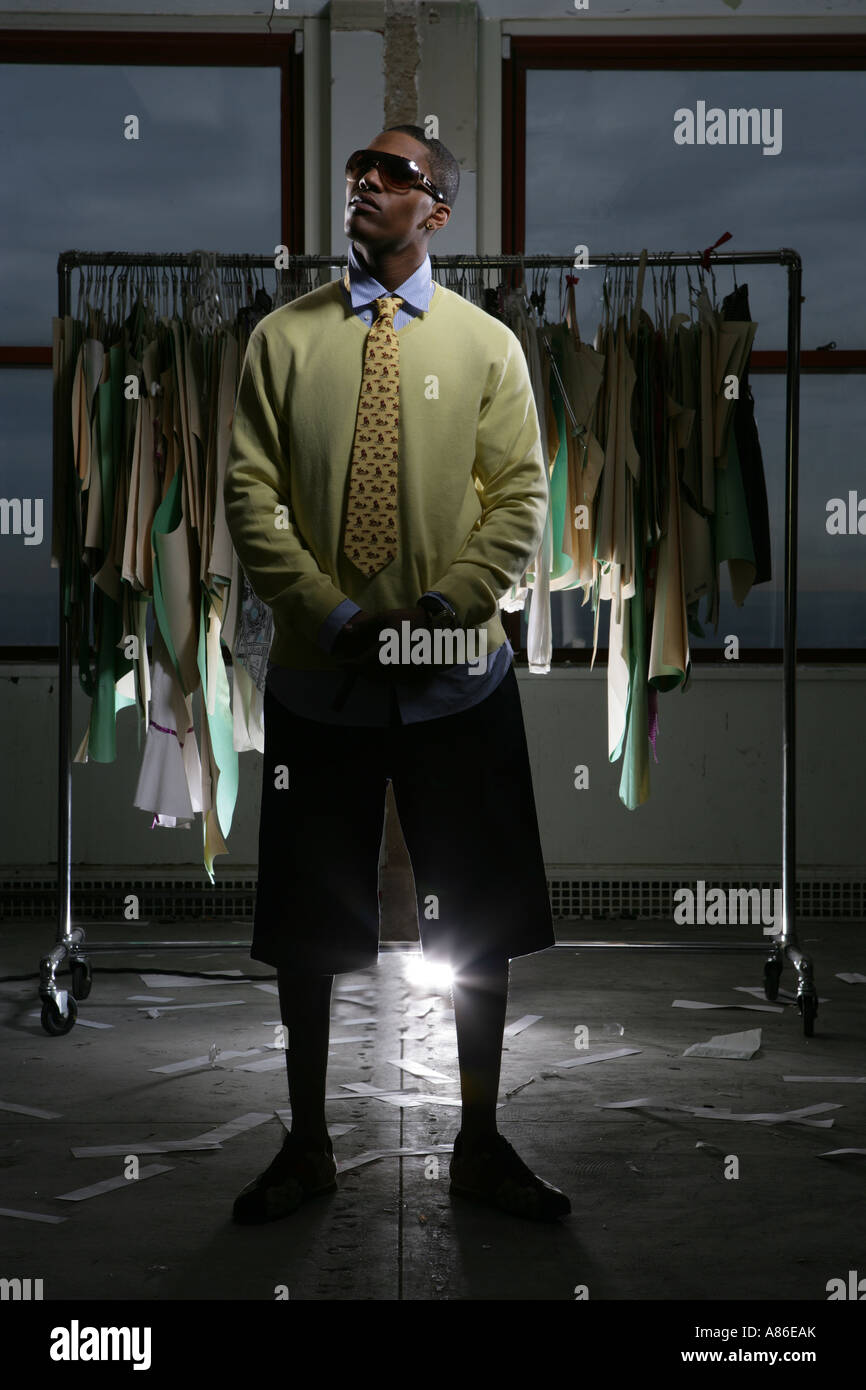 Young man standing in front of a clothing rack Stock Photo - Alamy