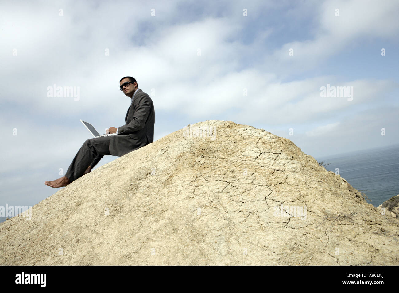 View of a man sitting on a cliff Stock Photo - Alamy
