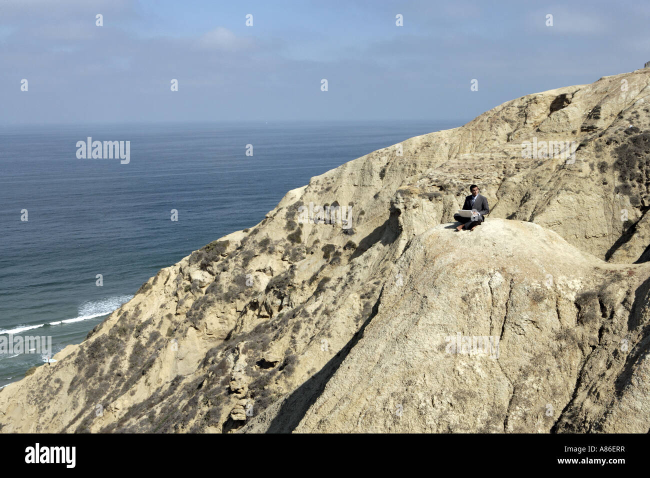 View of a man sitting on a cliff Stock Photo - Alamy