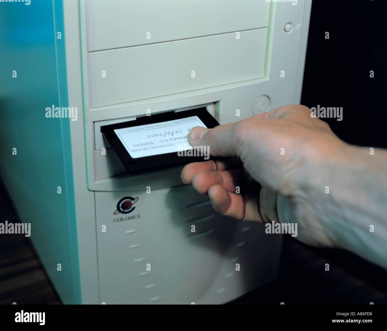 Inserting a floppy disc into the disc drive of a personal computer ...