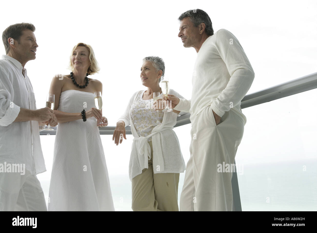 Four mature adults enjoying drinks on a terrace Stock Photo - Alamy