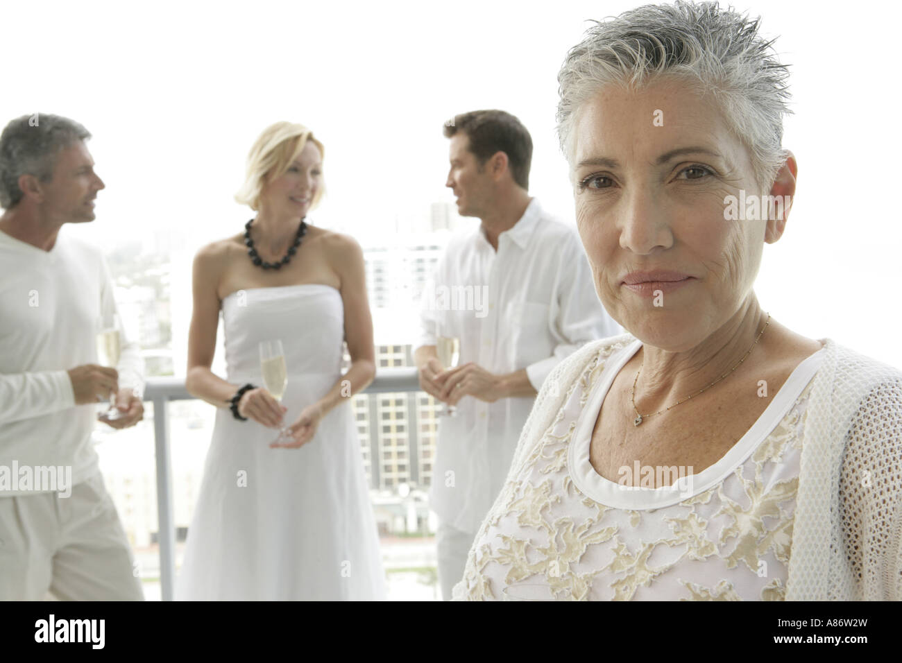 Four mature adults standing on a terrace having drinks Stock Photo - Alamy