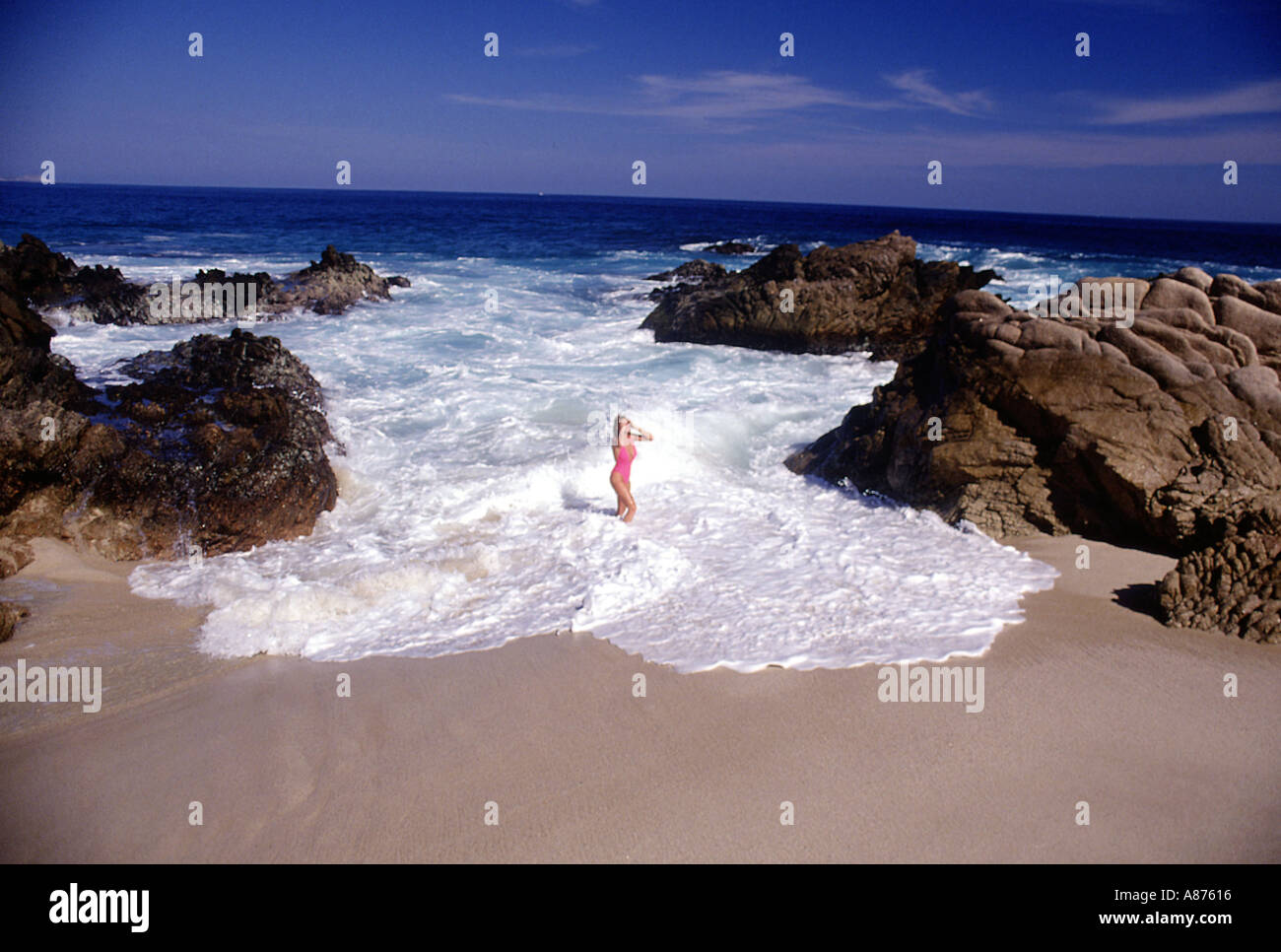 A woman splashing in the waves wearing a red bikini She is positioned ...