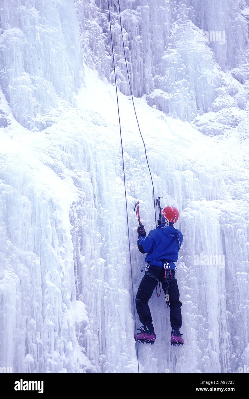 Ice climber wearing safety gear using ropes using picks ascending ...