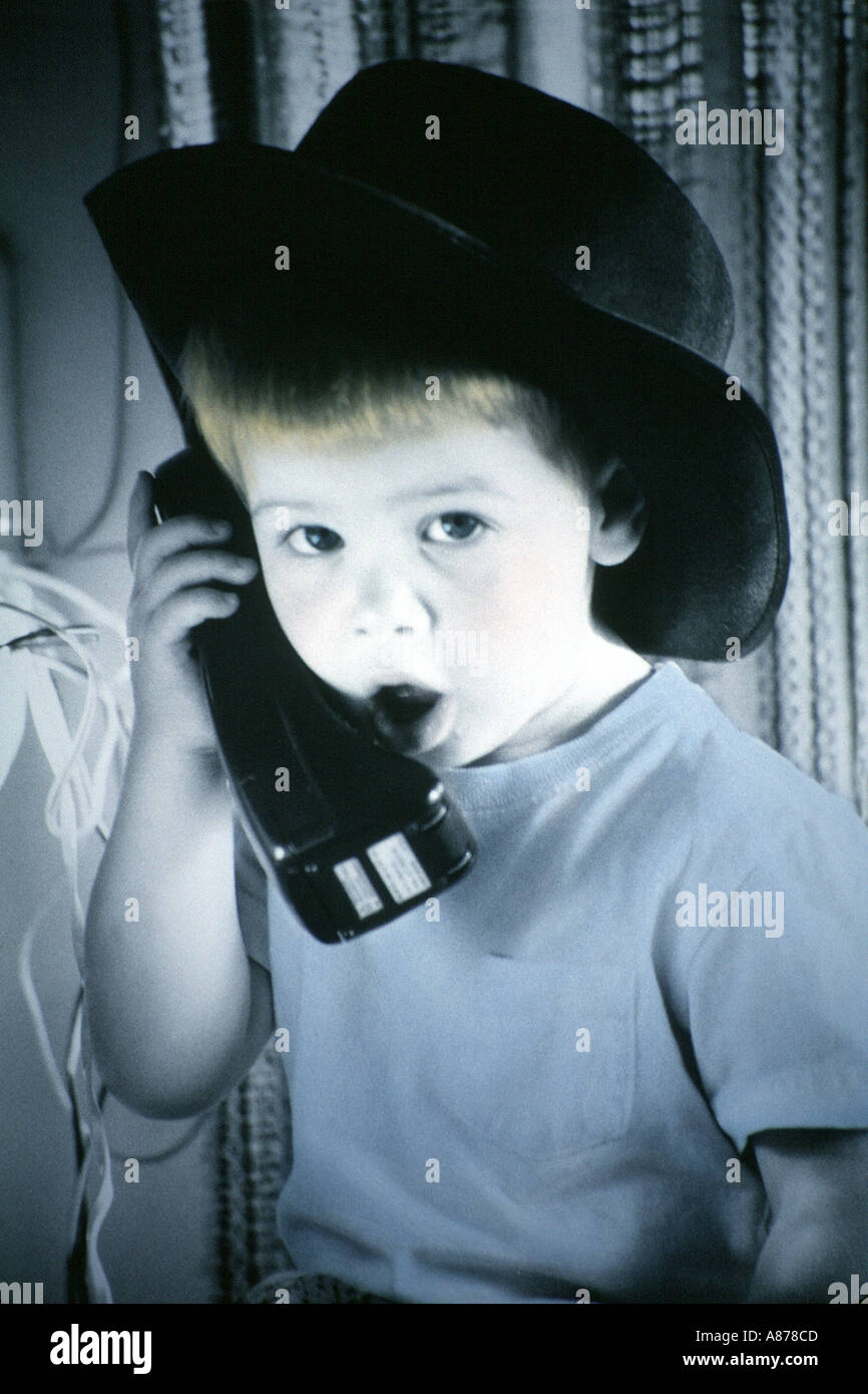A little boy wearing a cowboy hat talking on the phone. Hand colored ...