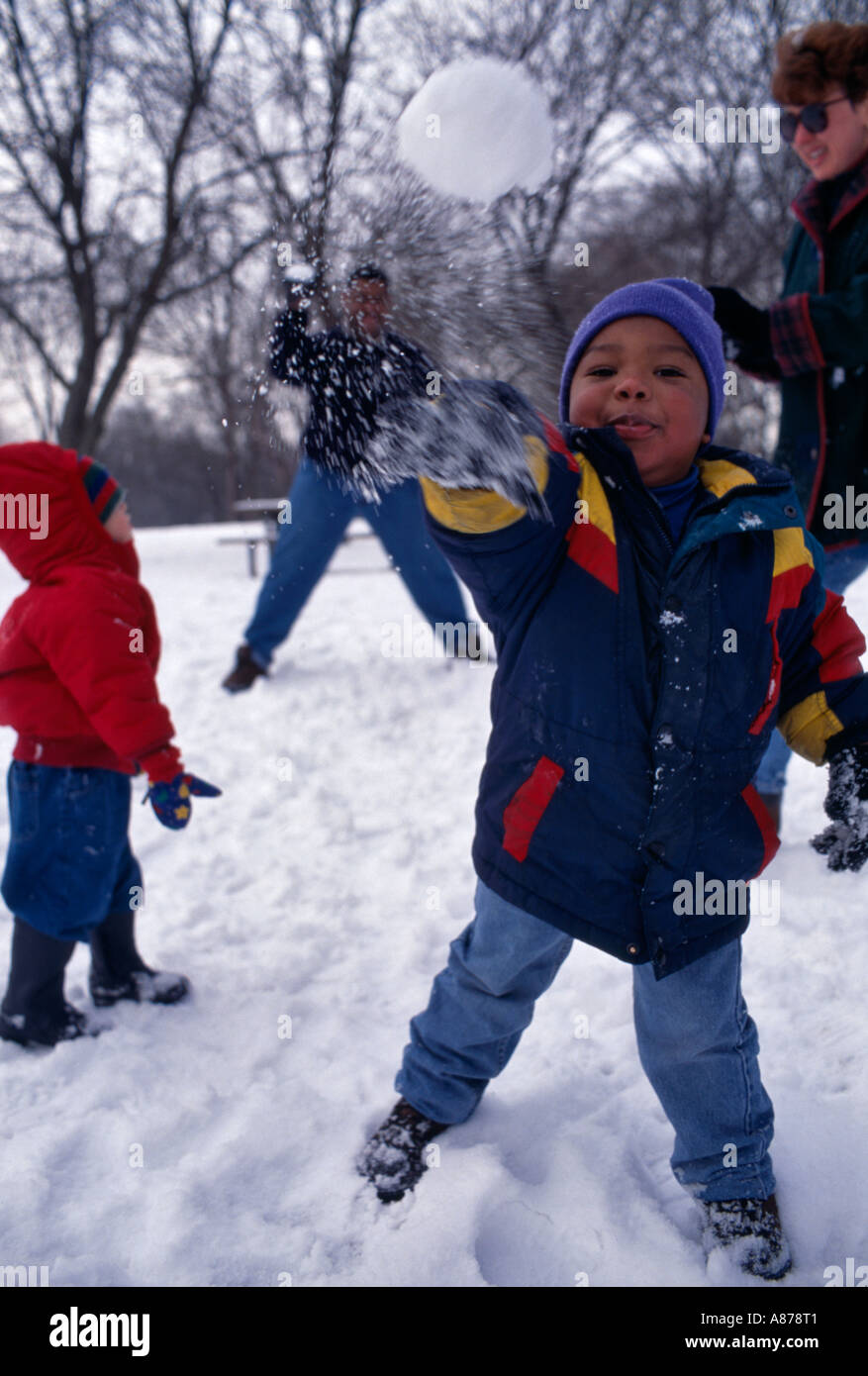 Young African American boy throwing a snowball at the camera with ...