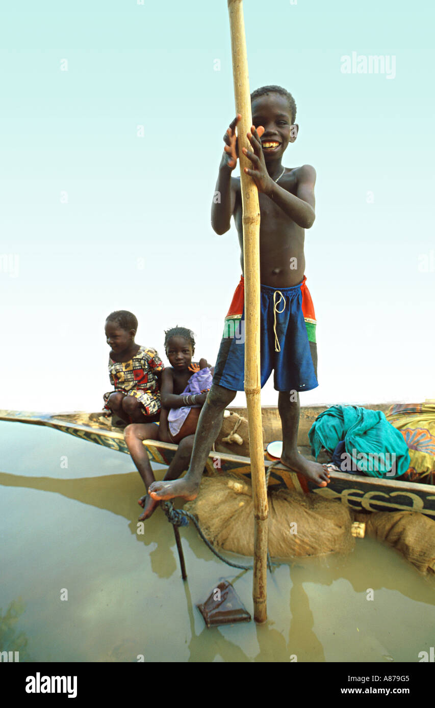 Young children from the Bozo tribe sitting in a traditional pirogue and ...