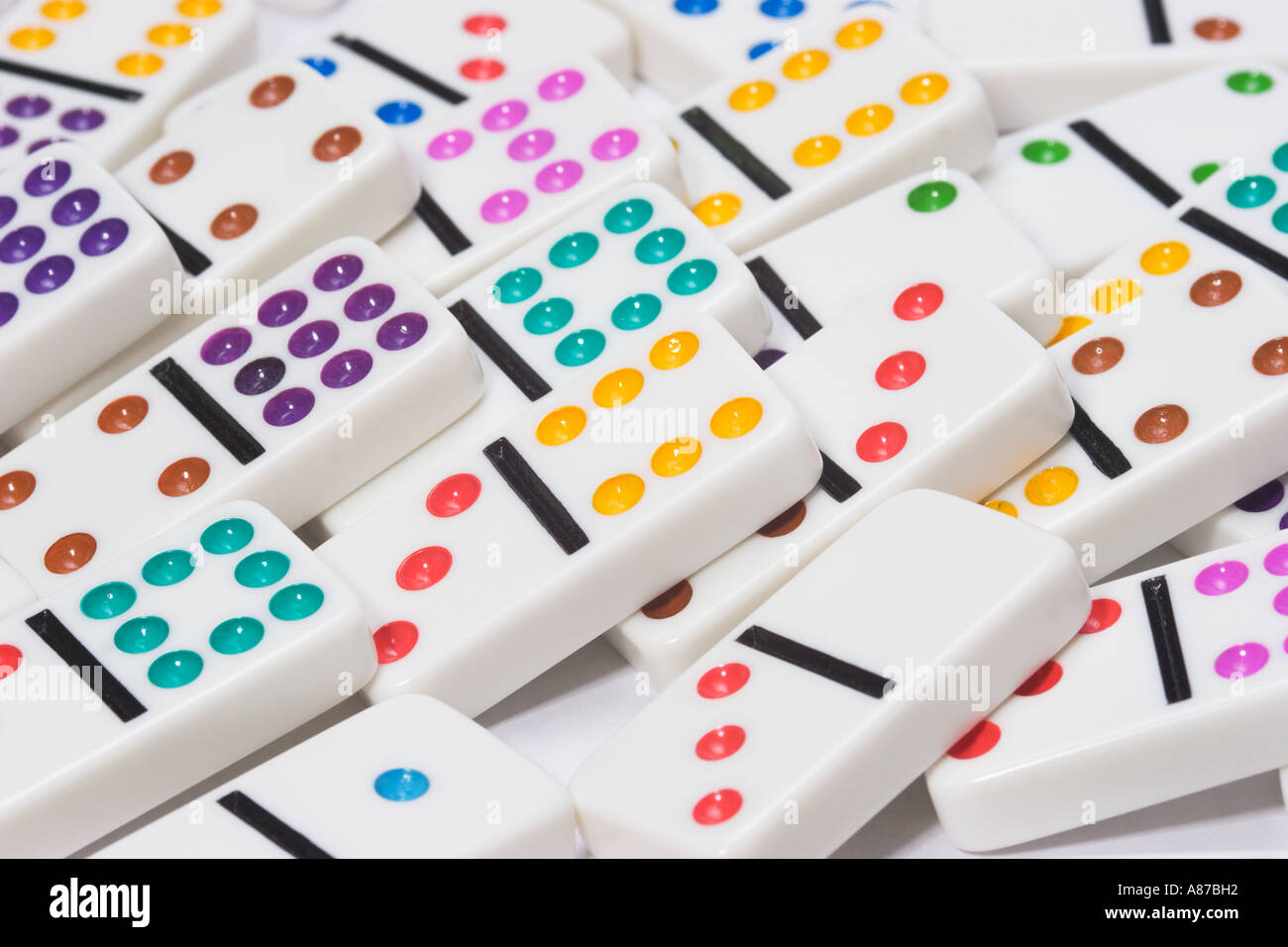 A pile of white dominoes with brightly colored dots used in playing ...