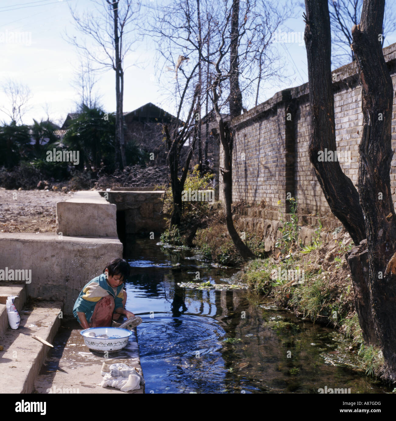 Local woman doing her laundry in a small stream,small village in Yunnan ...